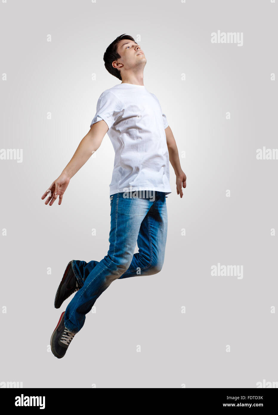 Modern slim hip-hop style man jumping dancing on a grey background ...