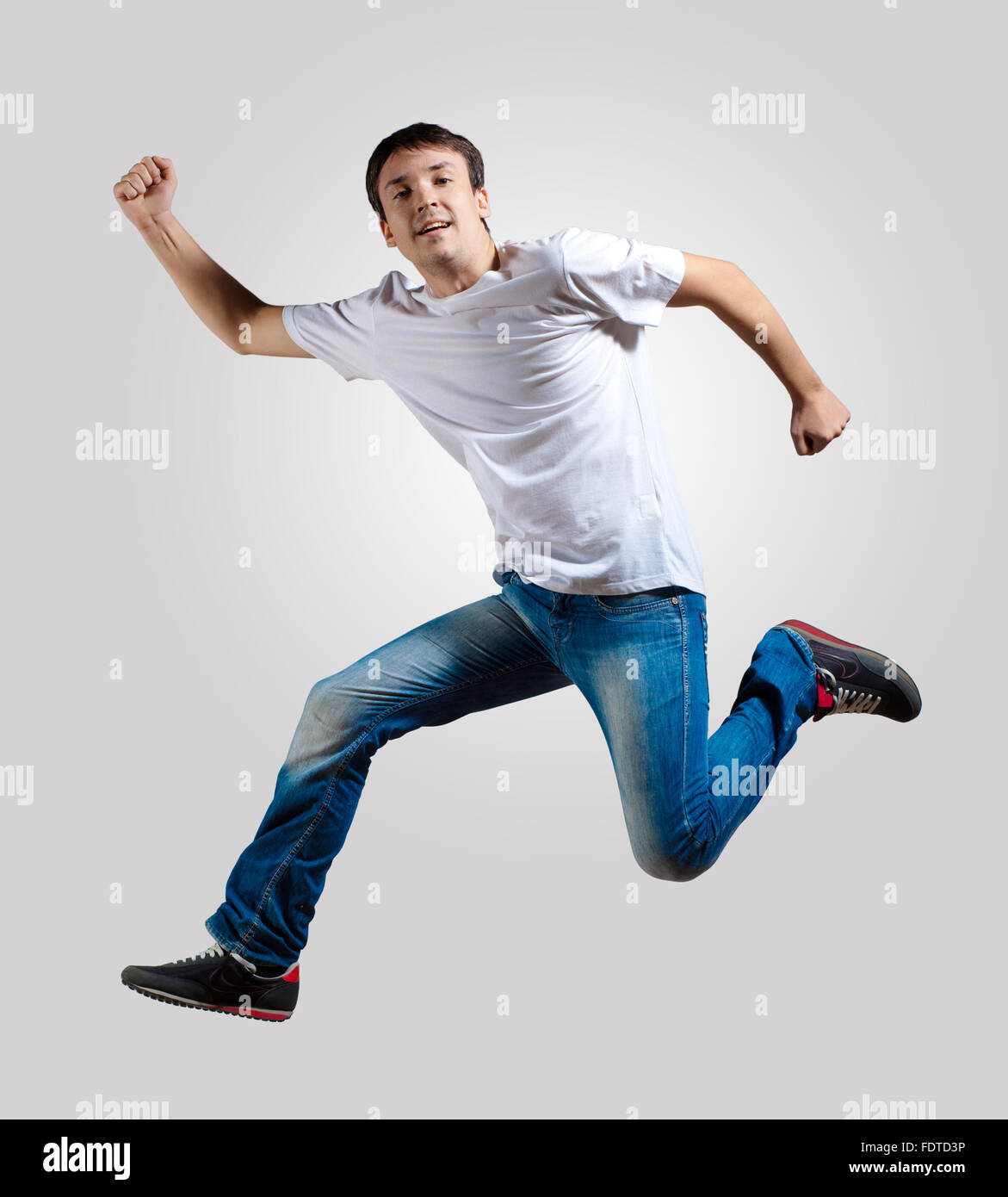 Modern slim hip-hop style man jumping dancing on a grey background ...