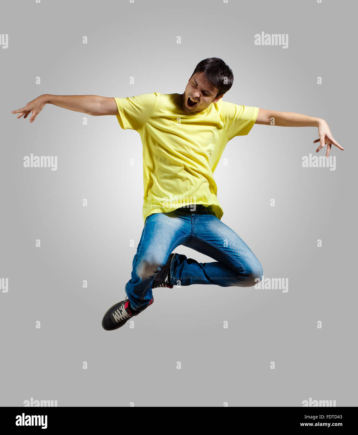 Modern slim hip-hop style man jumping dancing on a grey background ...