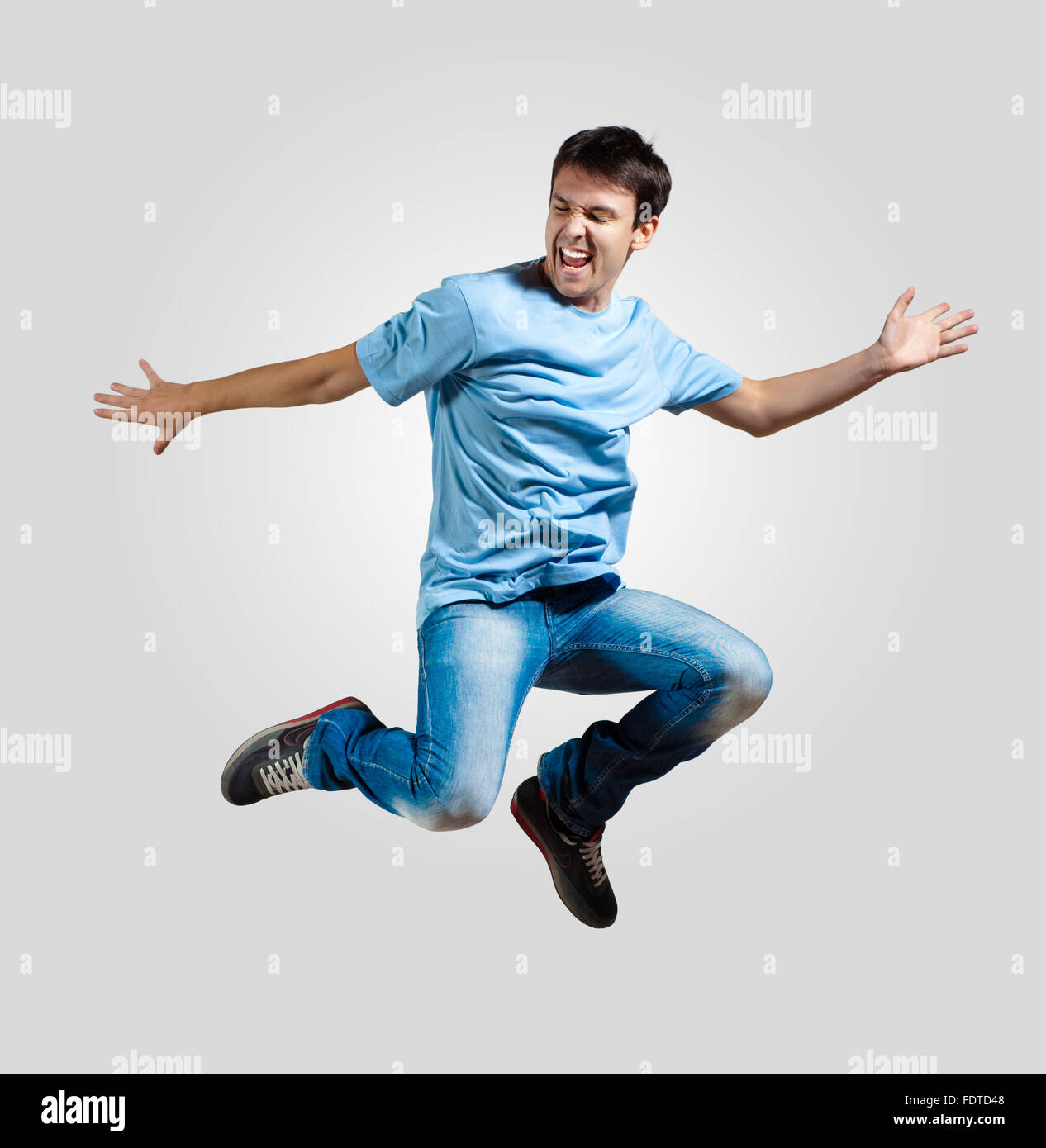 Modern slim hip-hop style man jumping dancing on a grey background ...