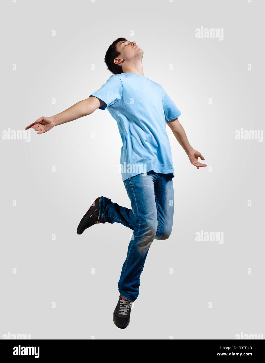 Modern slim hip-hop style man jumping dancing on a grey background ...
