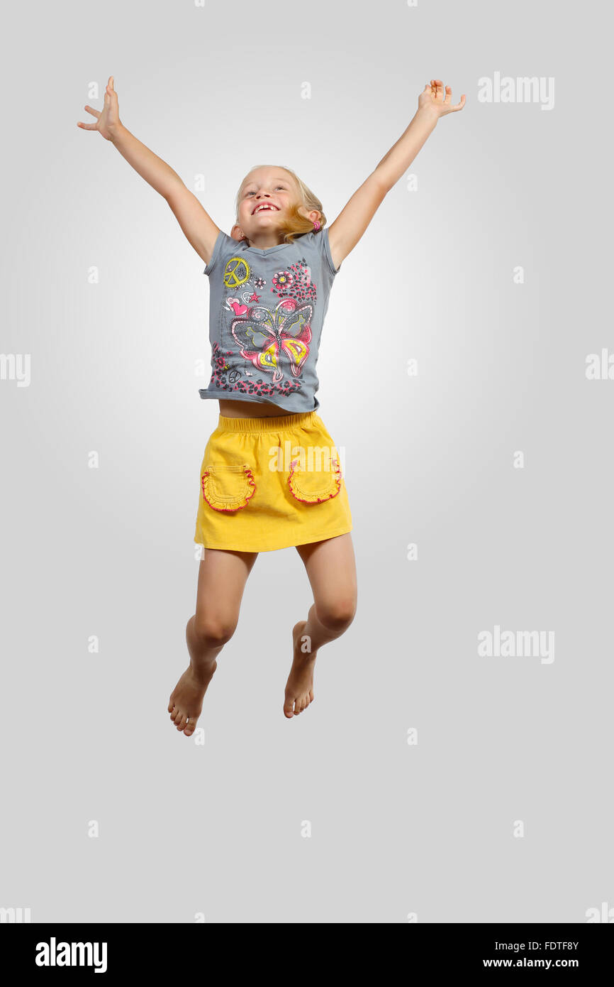Photo of little girl jumping and raising hands against grey background ...