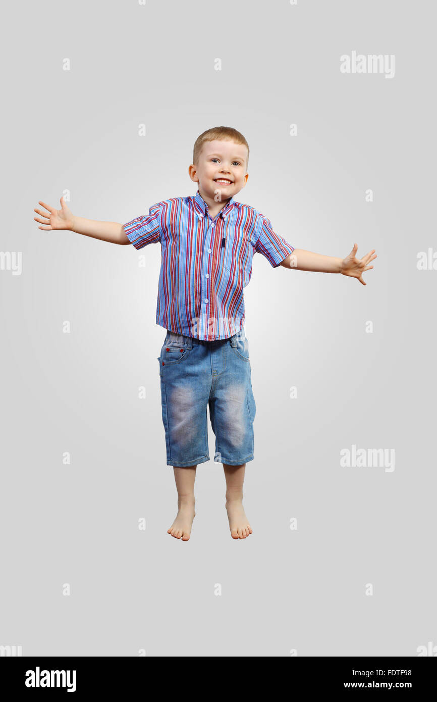 Photo of little boy jumping and raising hands against grey background ...