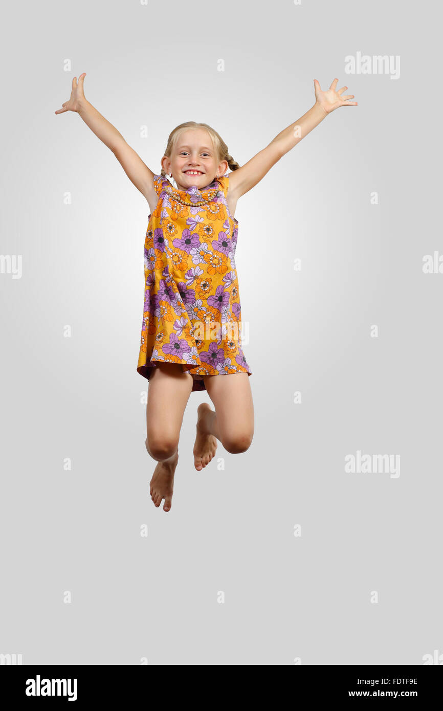 Photo of little girl jumping and raising hands against grey background ...