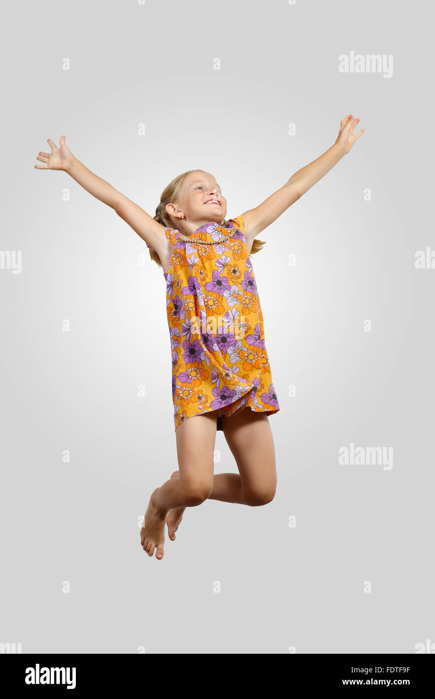 Photo of little girl jumping and raising hands against grey background ...