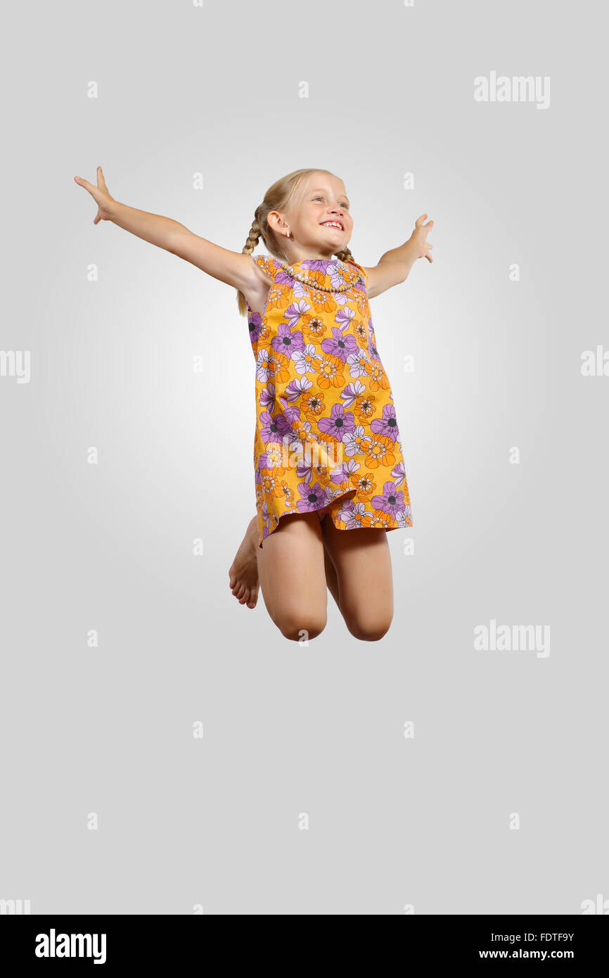 Photo of little girl jumping and raising hands against grey background ...