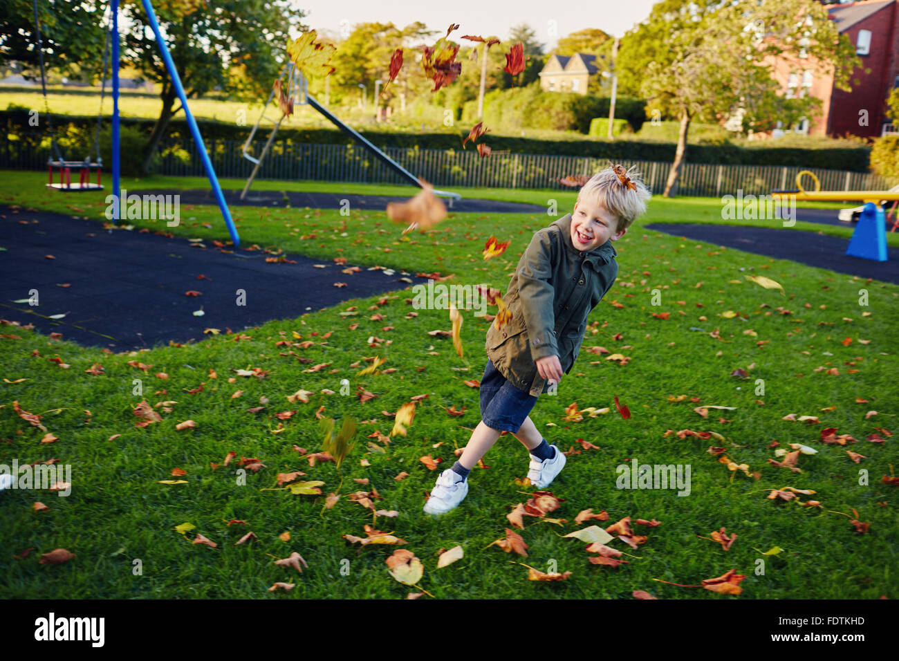 Young boy throwing leaves in the park having fun Stock Photo - Alamy