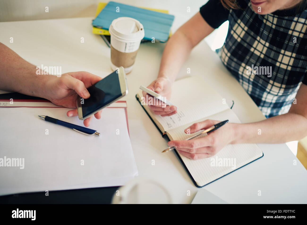 Two students using their smart phones whilst studying Stock Photo - Alamy