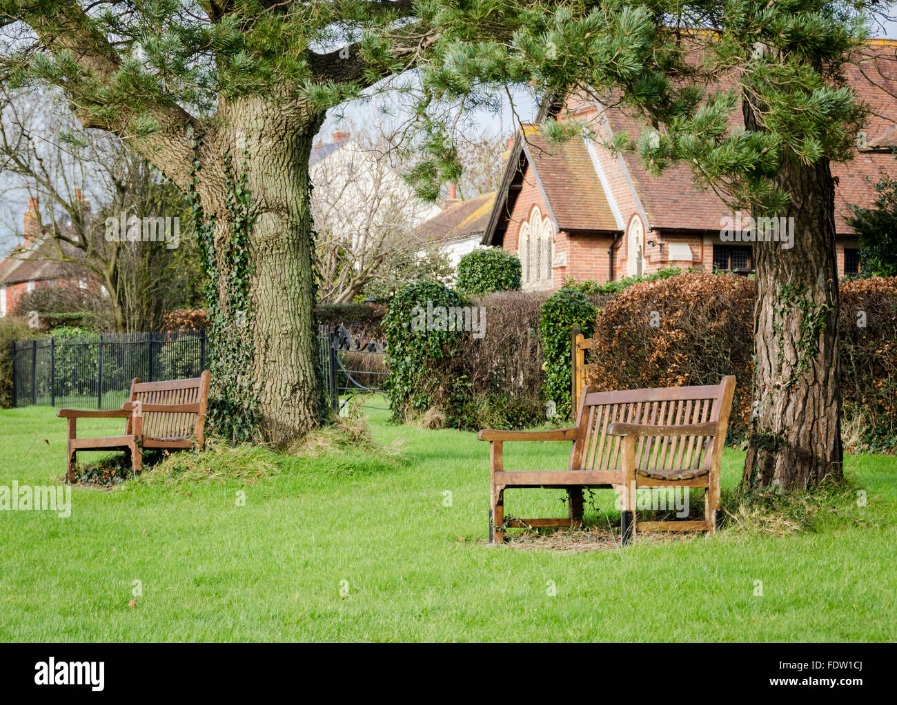 Benches under trees in the village of Woodchurch, Kent, UK Stock Photo ...
