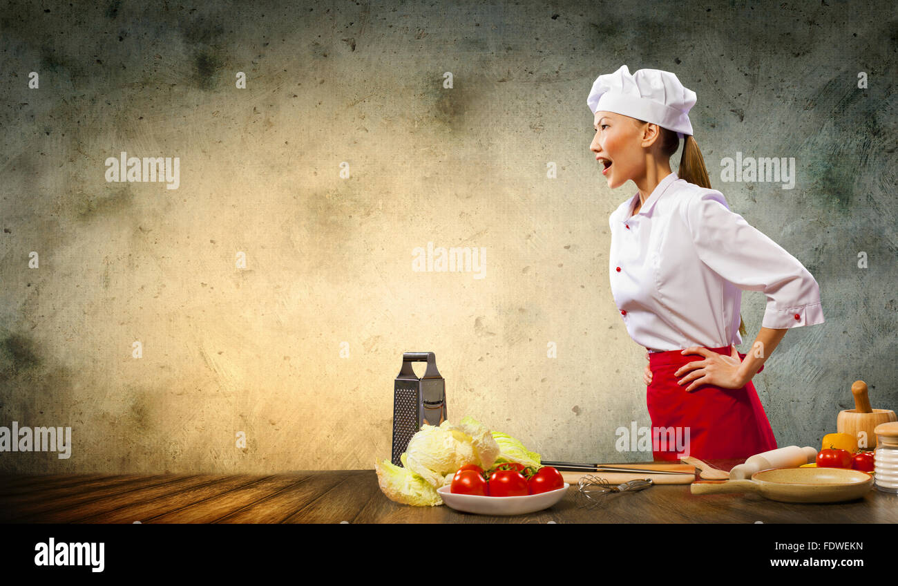 Asian female cook in anger against color background with shine effects ...