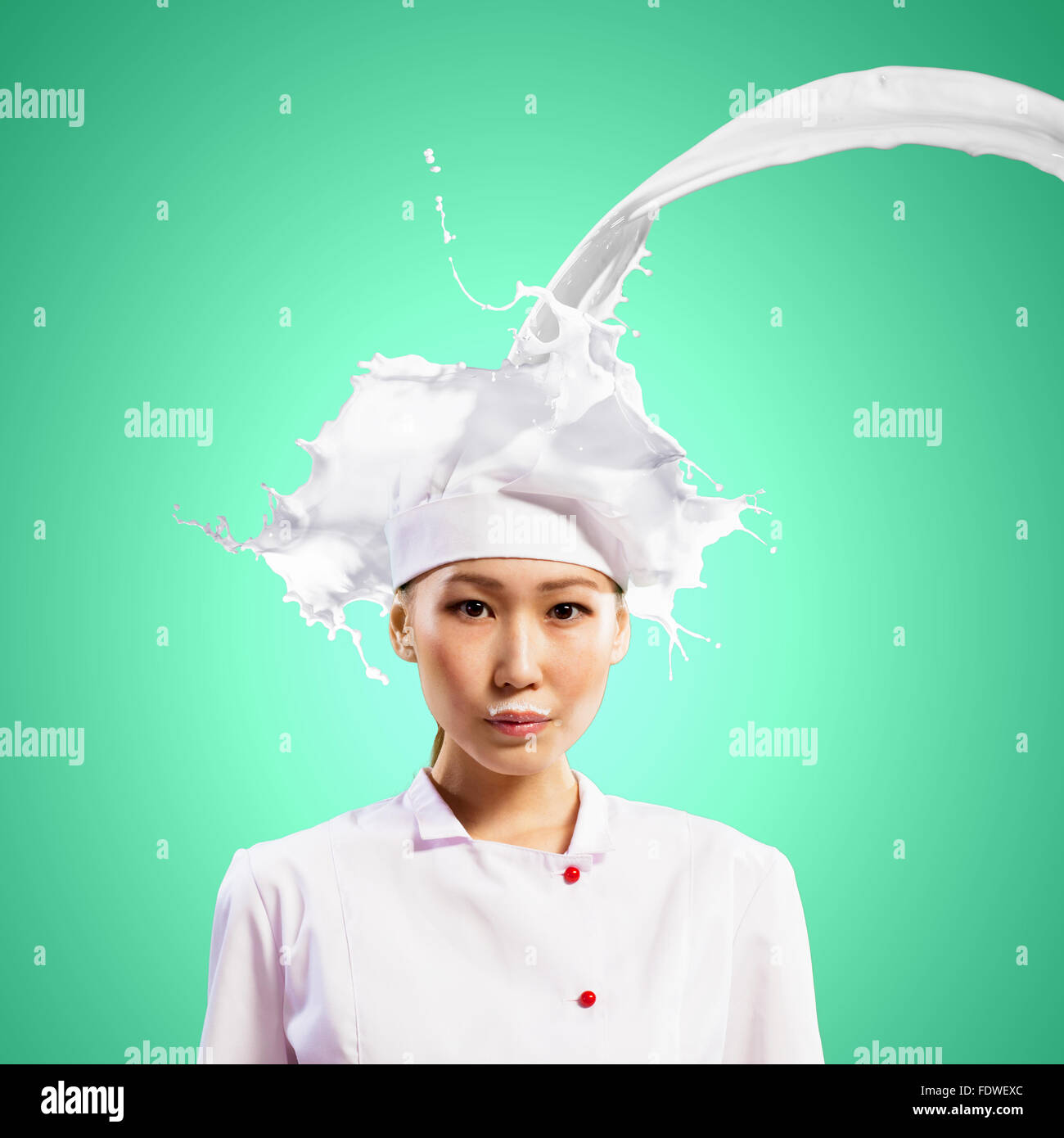 Asian female cook standing against milk splashes in red apron against ...