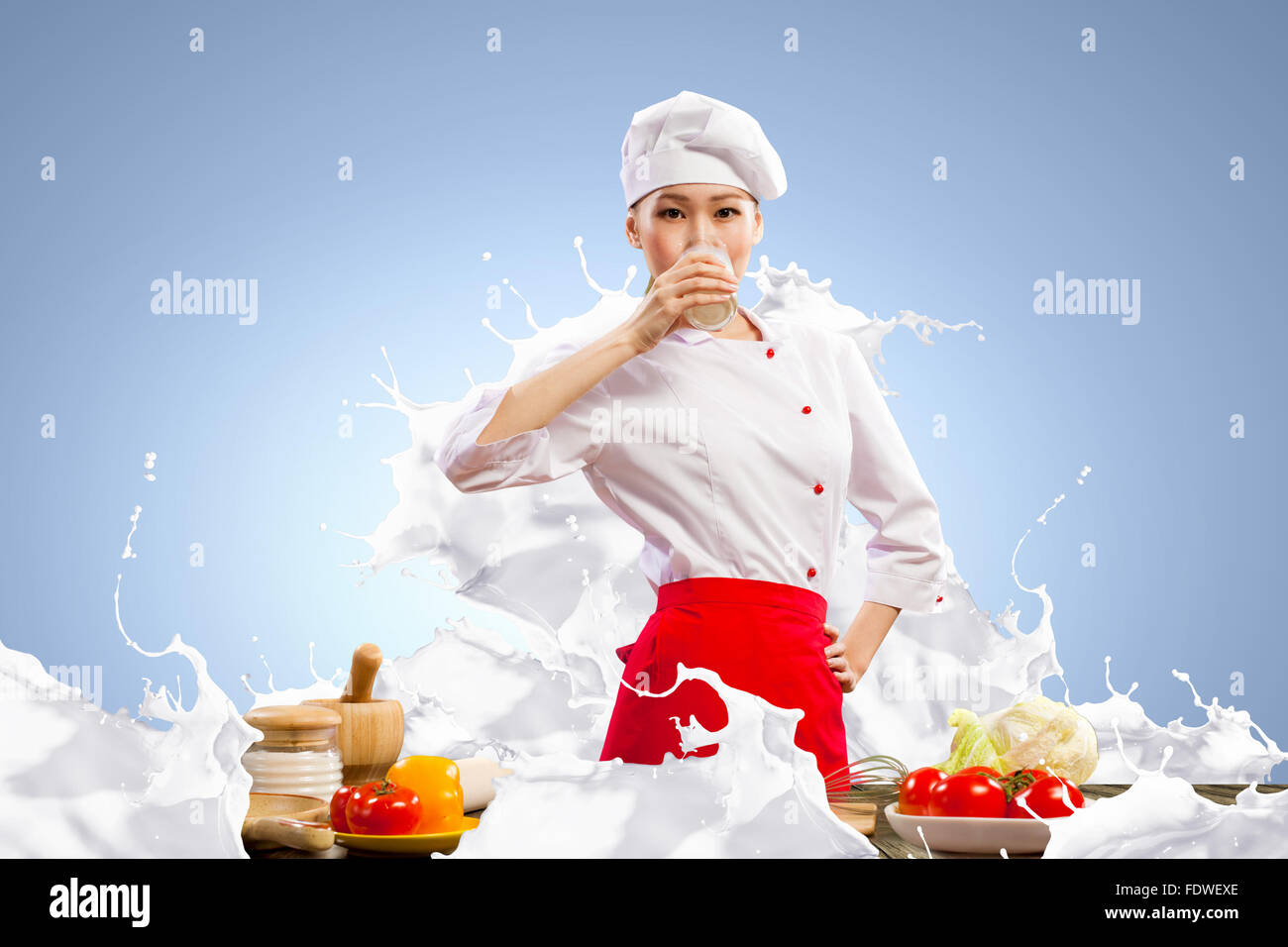 Asian female cook against milk splashes in red apron against color ...