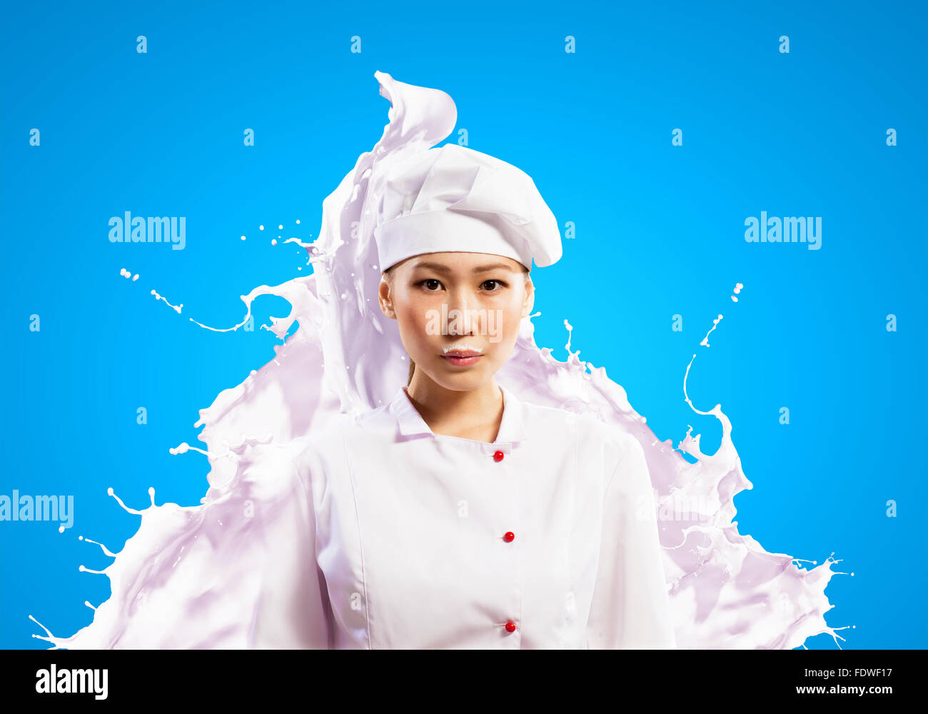 Asian female cook against milk splashes in red apron against color ...