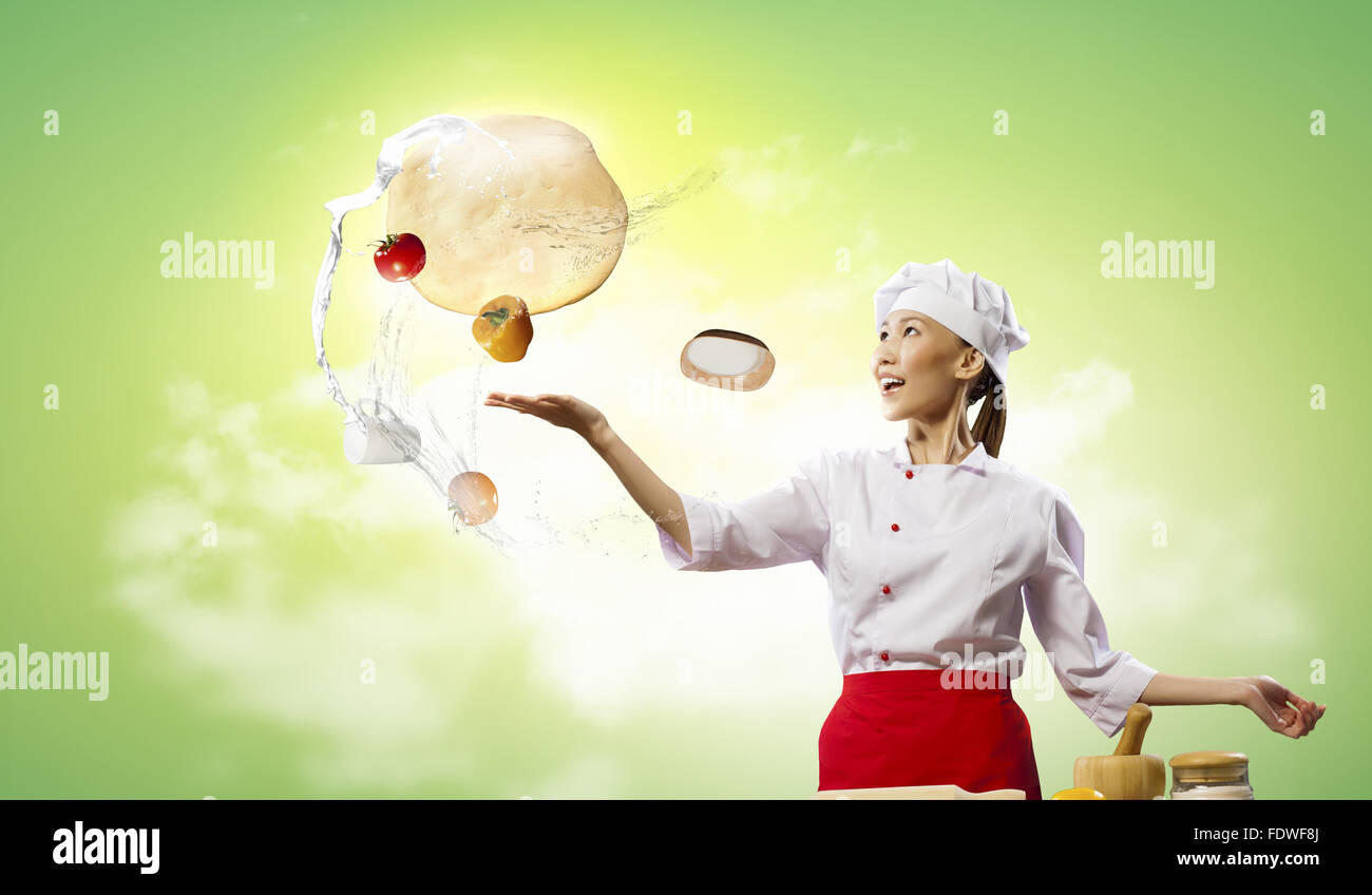 Asian female cook making pizza standing against color background Stock ...