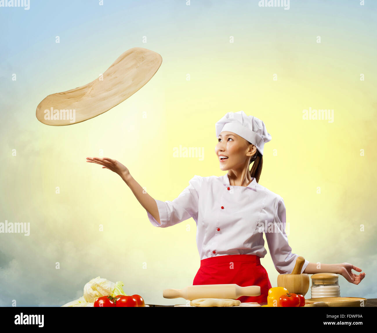 Asian female cook making pizza standing against color background Stock ...