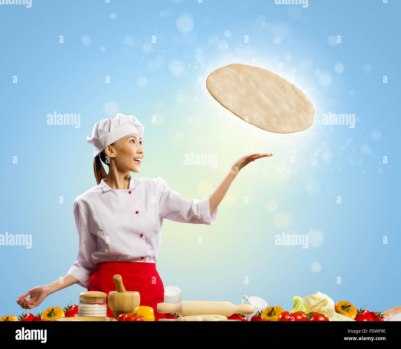Asian female cook making pizza standing against color background Stock ...