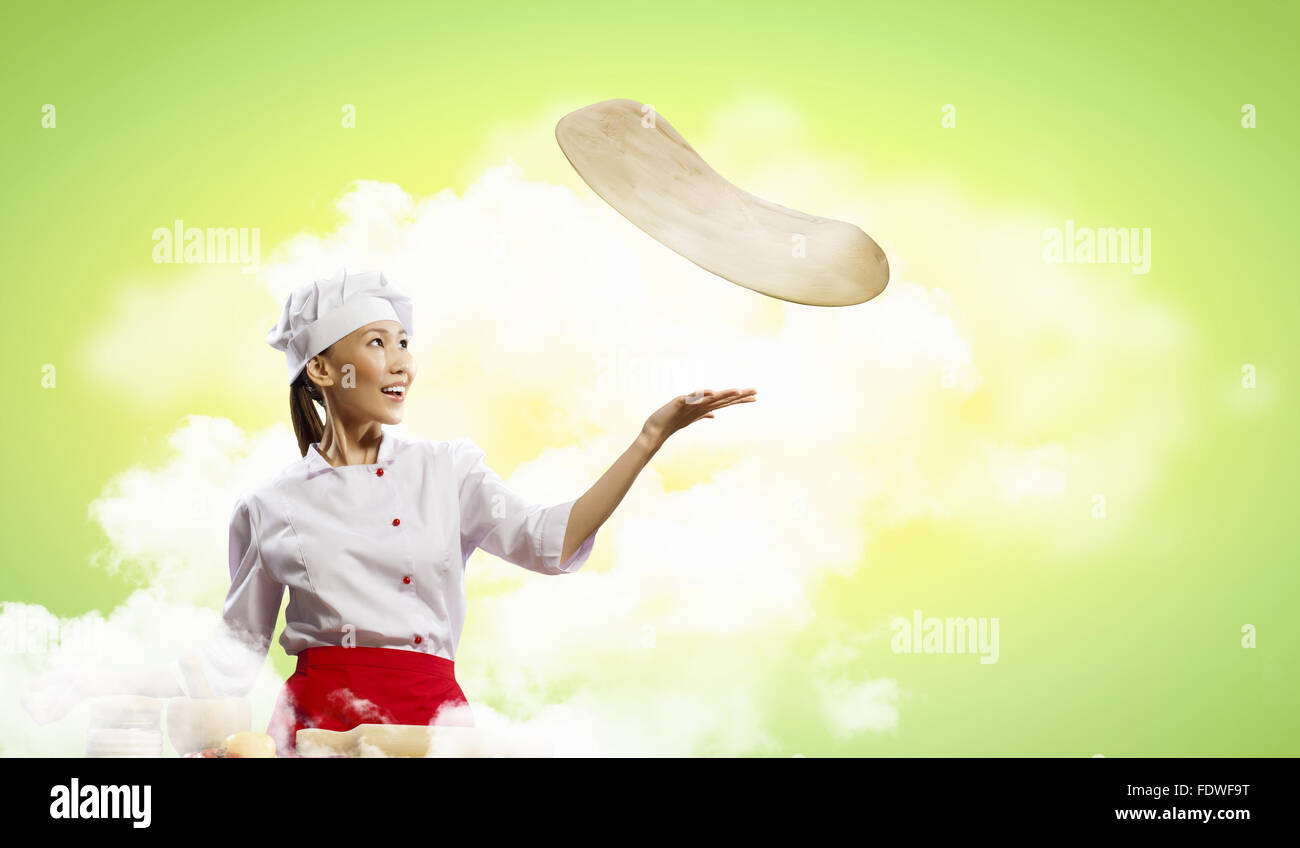 Asian female cook making pizza standing against color background Stock ...