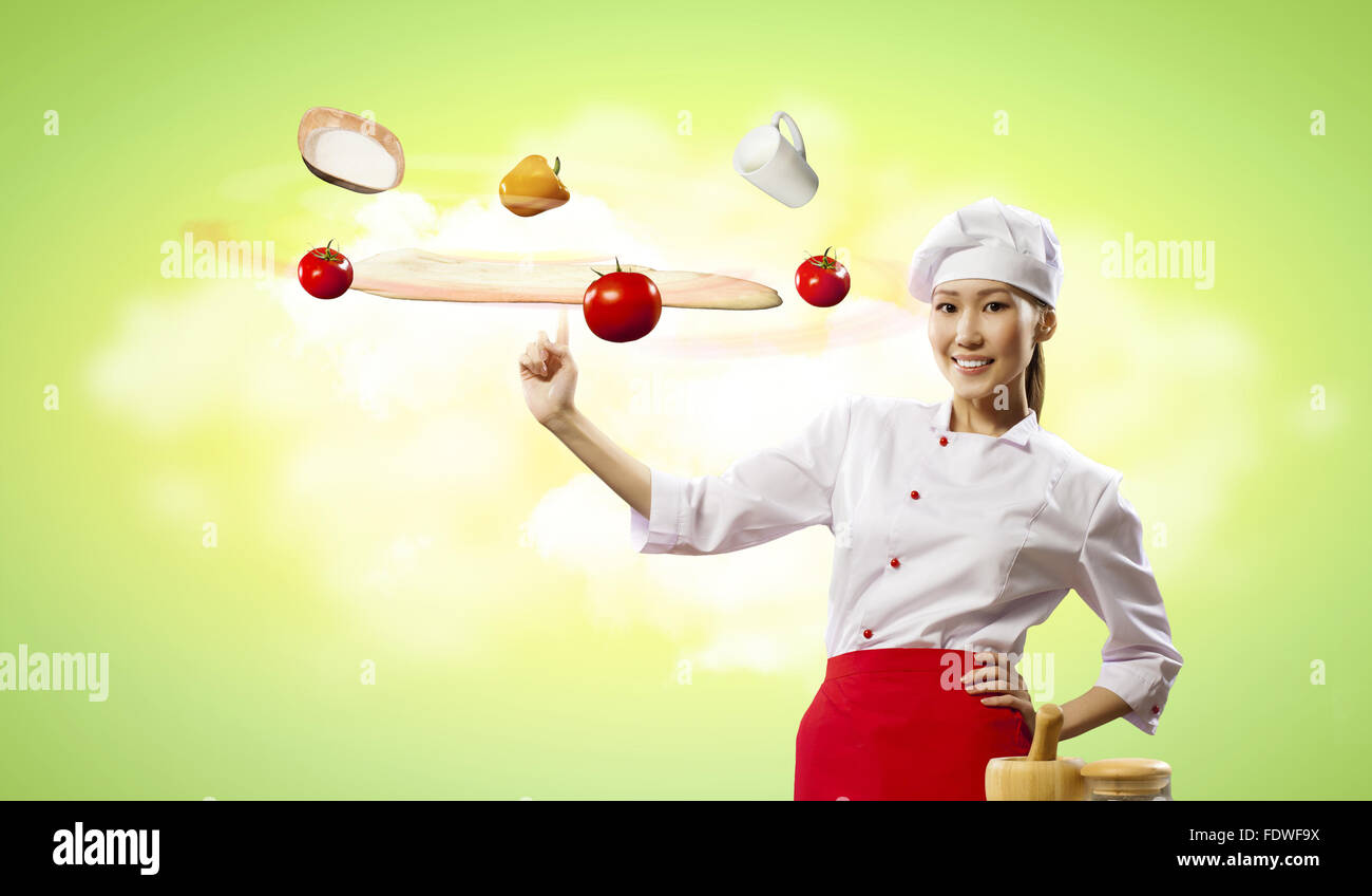 Asian female cook making pizza standing against color background Stock ...