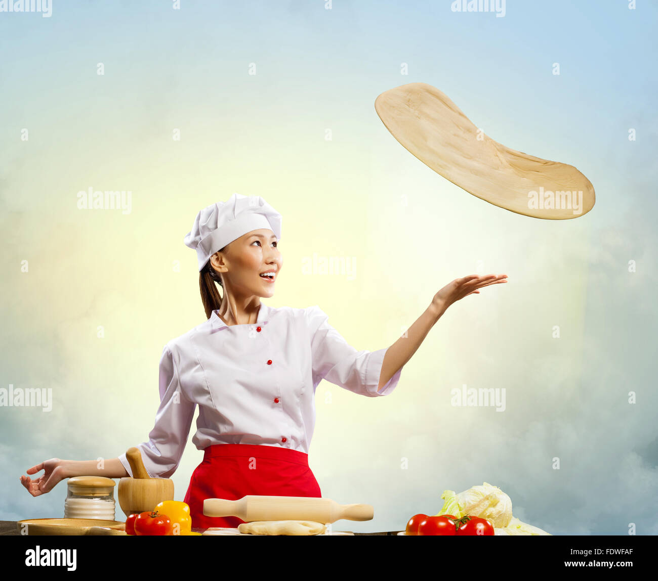 Asian female cook making pizza standing against color background Stock ...