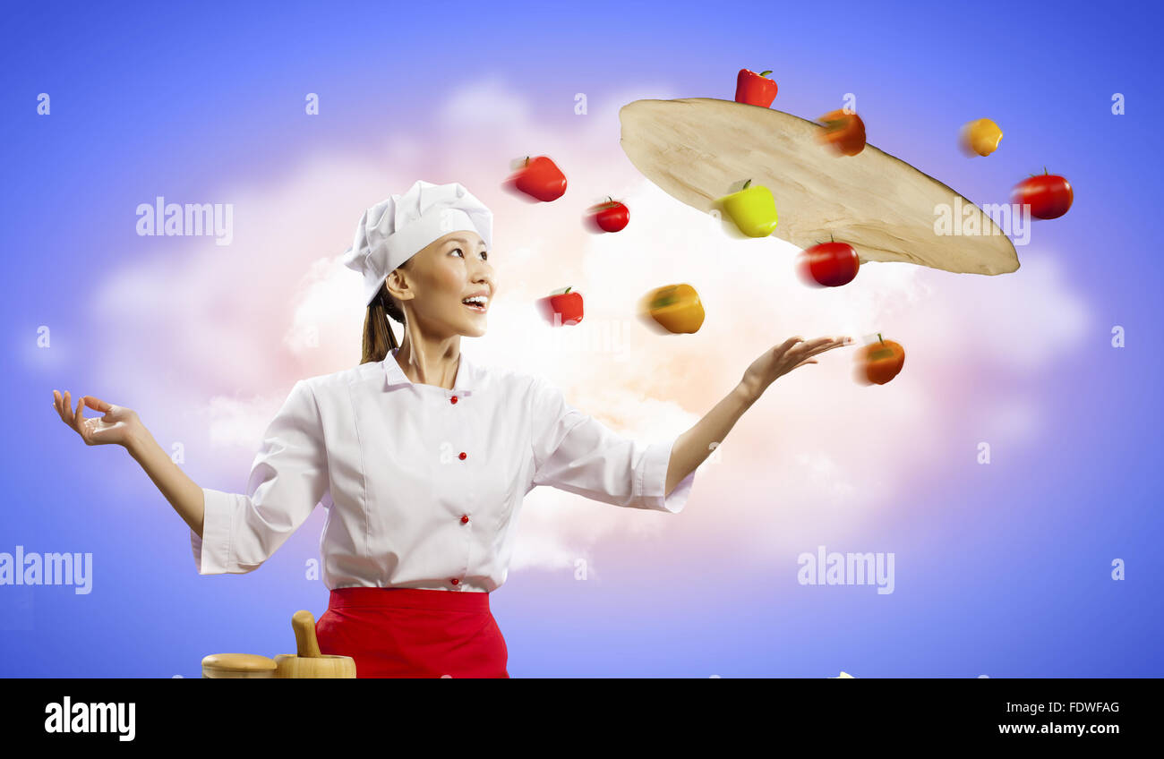 Asian female cook making pizza standing against color background Stock ...