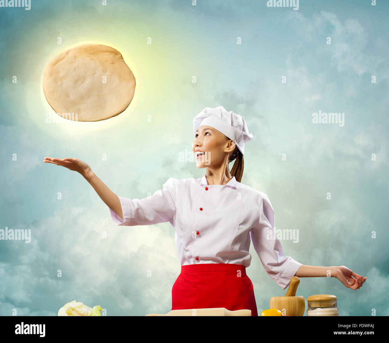 Asian female cook making pizza standing against color background Stock ...