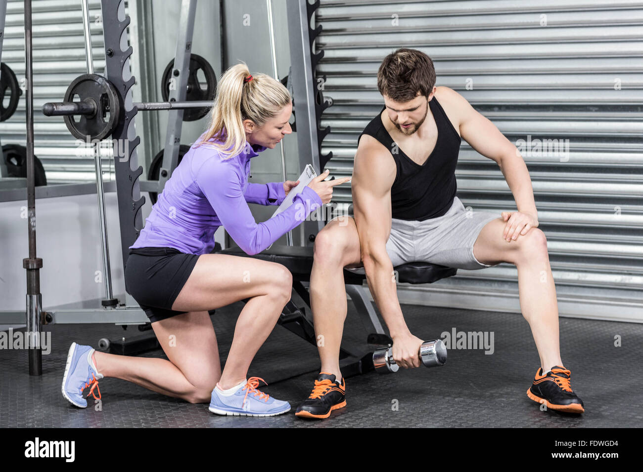 Female trainer assisting man with dumbbells Stock Photo - Alamy