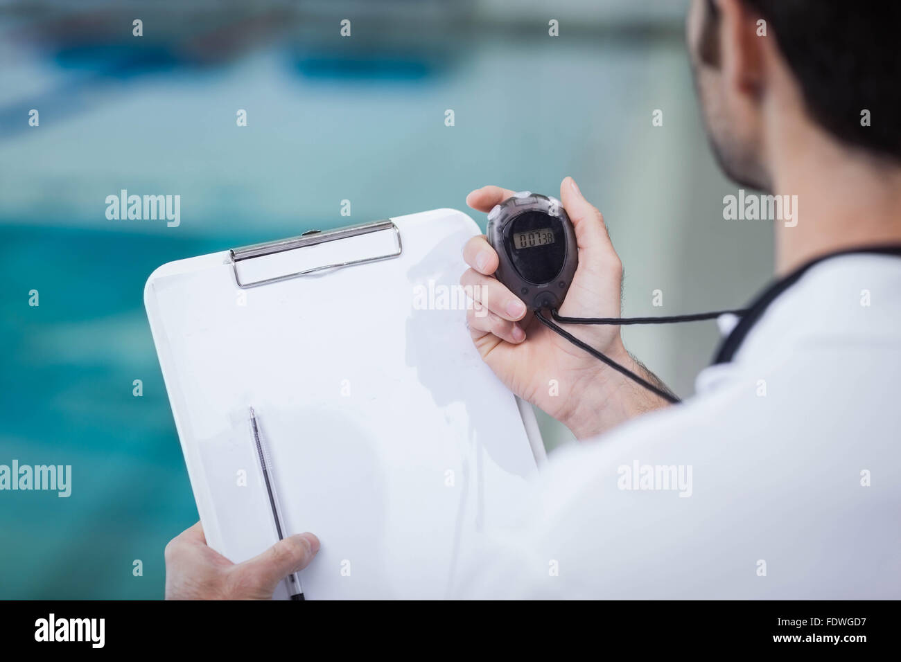 Handsome trainer holding stopwatch and reading clipboard Stock Photo ...