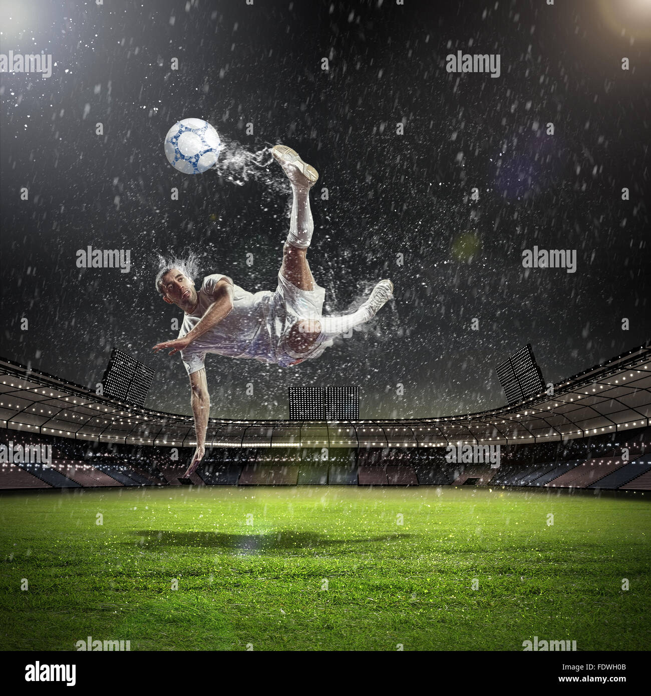 football player in white shirt striking the ball at the stadium under ...