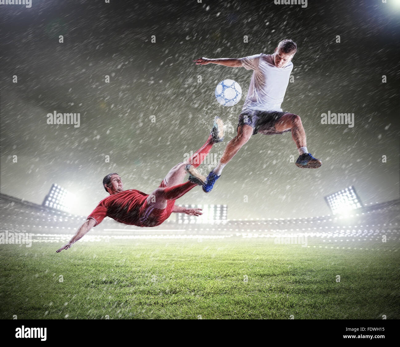 two football players in jump to strike the ball at the stadium Stock ...