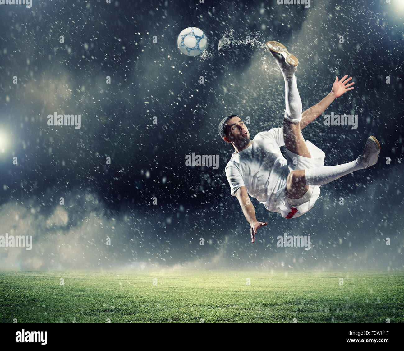 football player in white shirt striking the ball at the stadium under ...