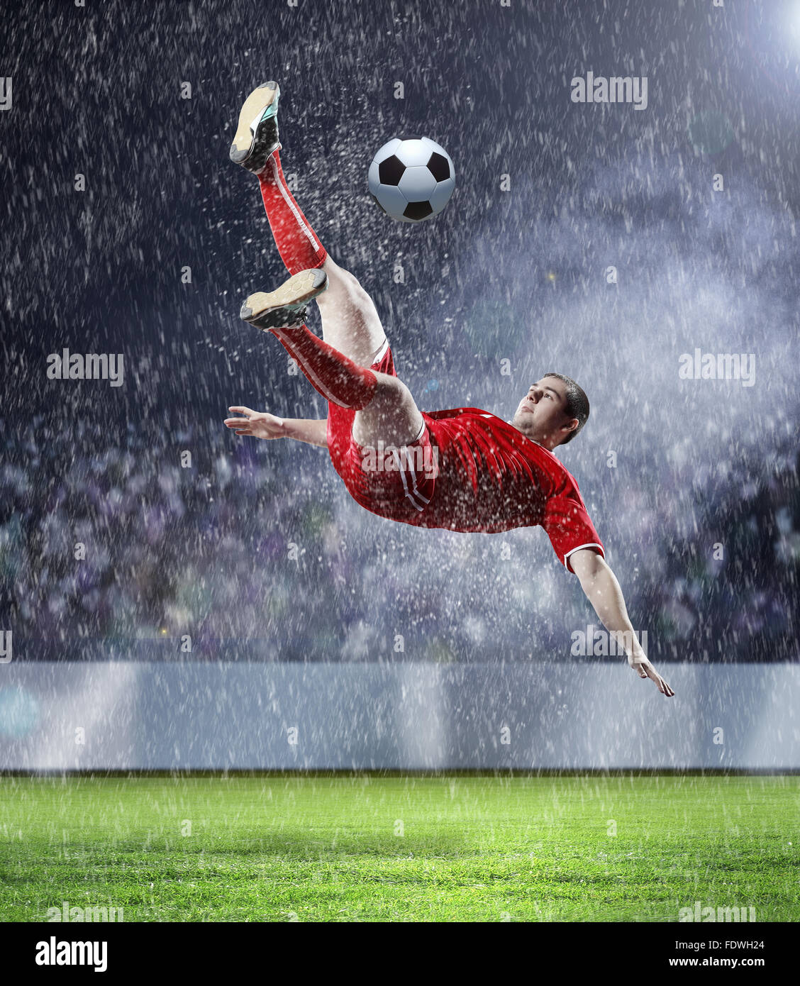 football player in red shirt striking the ball at the stadium under ...