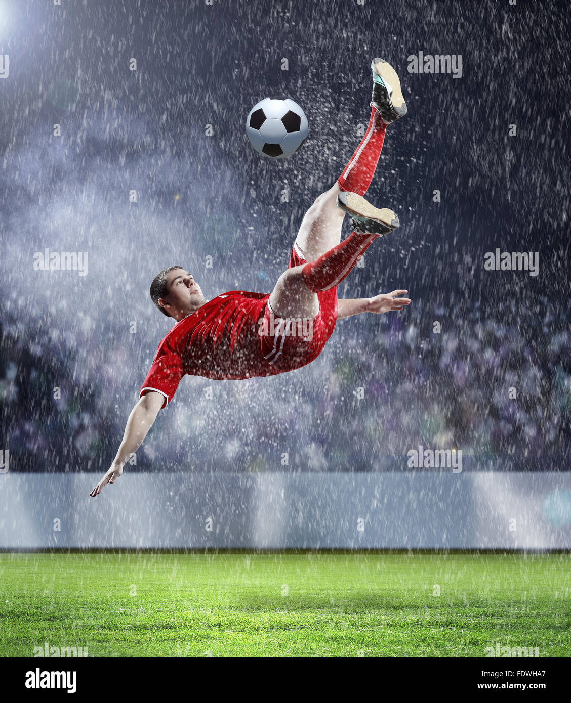 football player in red shirt striking the ball at the stadium under ...
