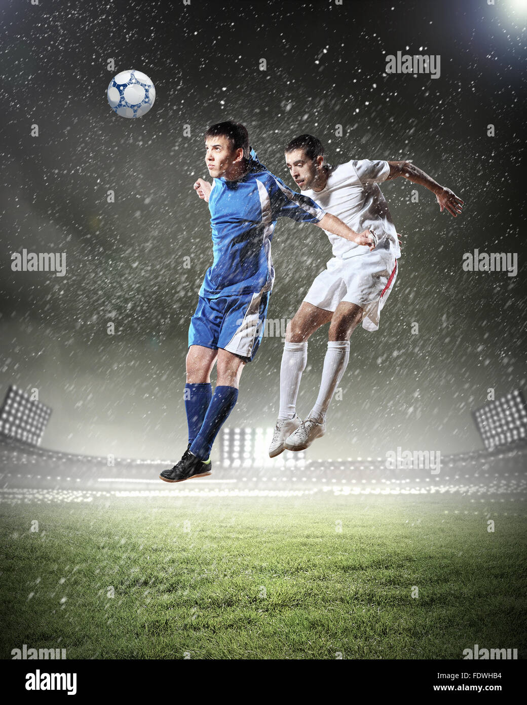 two football players in jump to strike the ball at the stadium under ...