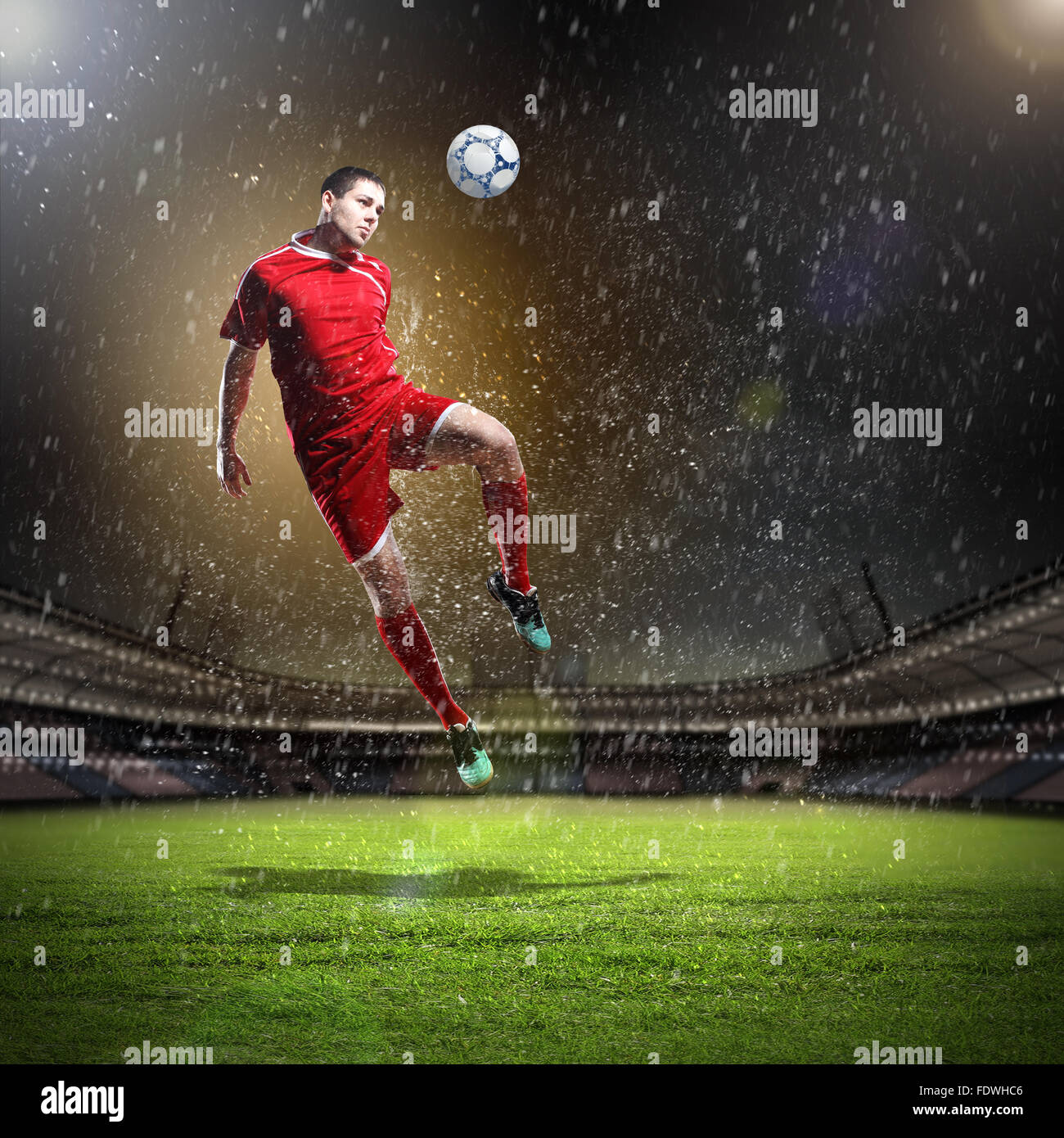 football player in red shirt striking the ball at the stadium under ...