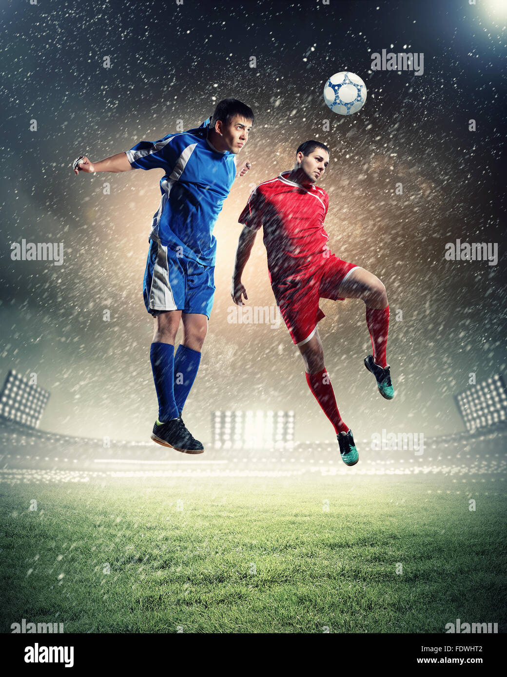 two football players in jump to strike the ball at the stadium Stock ...