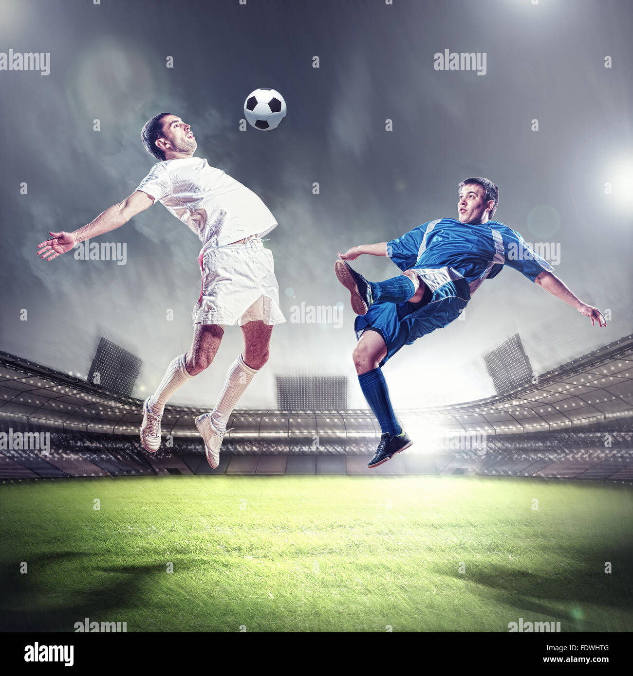 two football players in jump to strike the ball at the stadium Stock ...