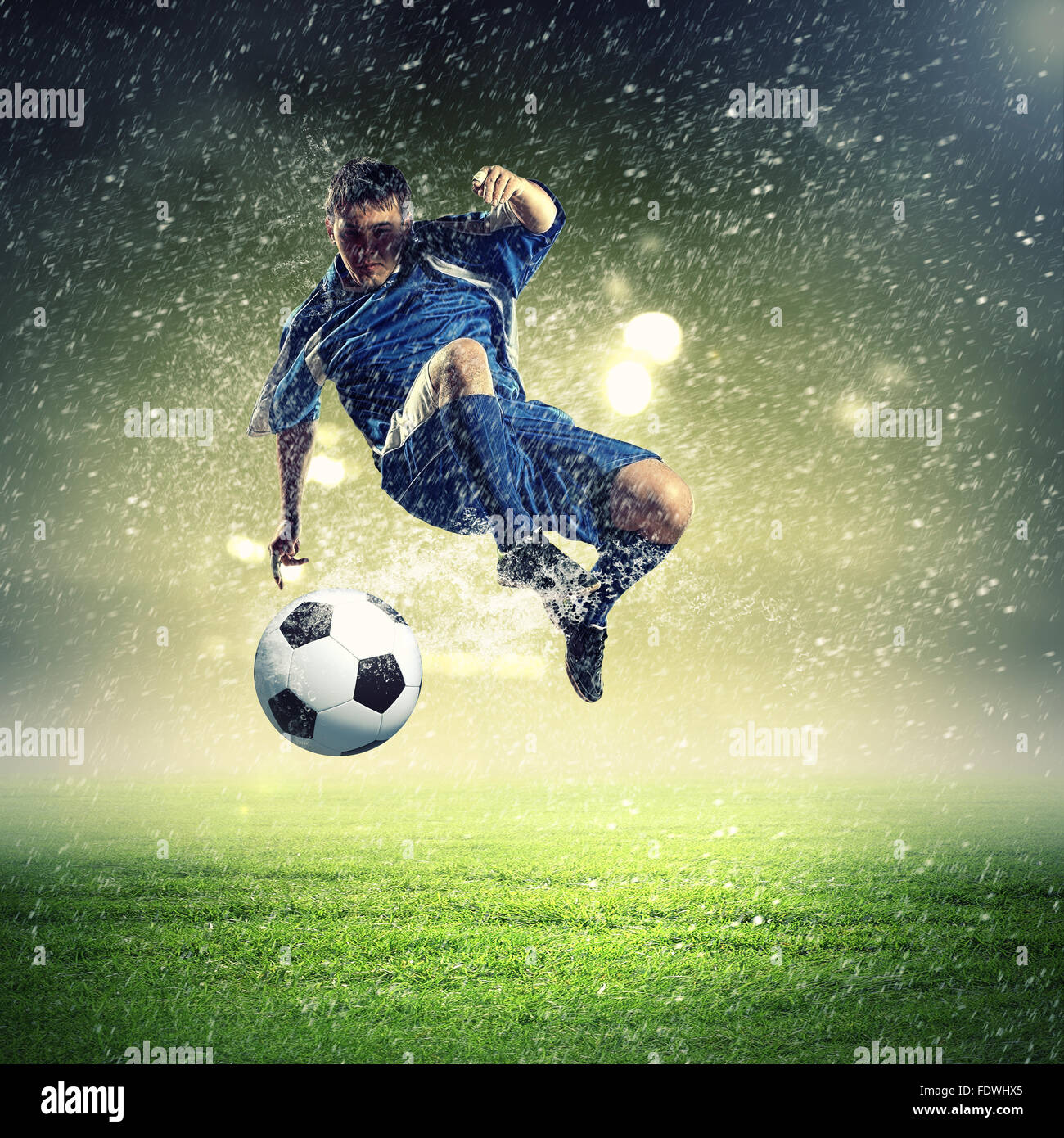 football player in blue shirt striking the ball aloft at the stadium ...