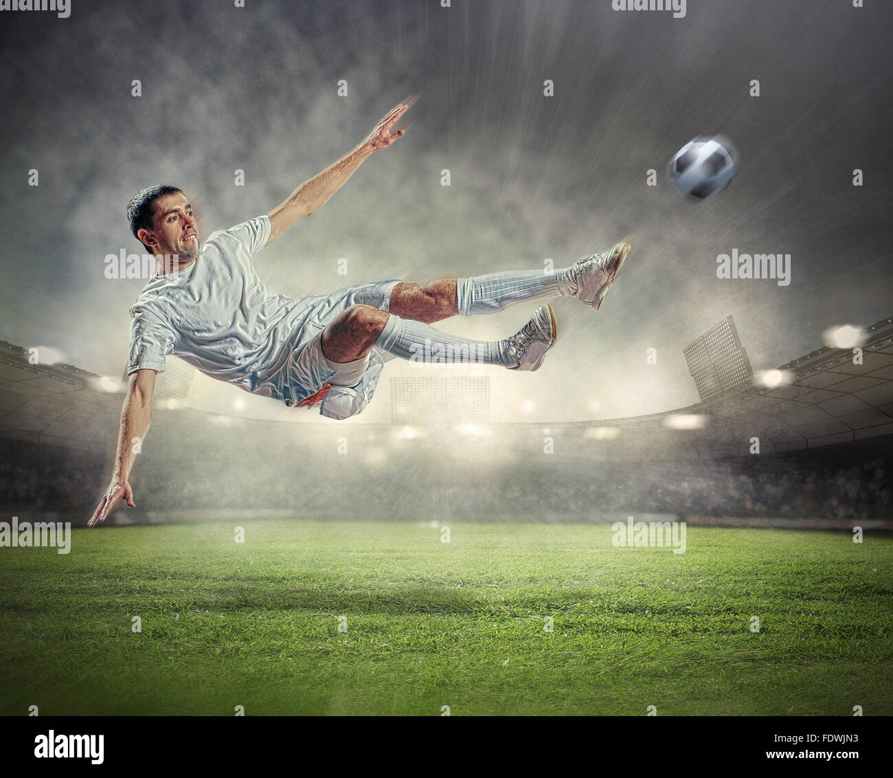 football player in white shirt striking the ball at the stadium under ...