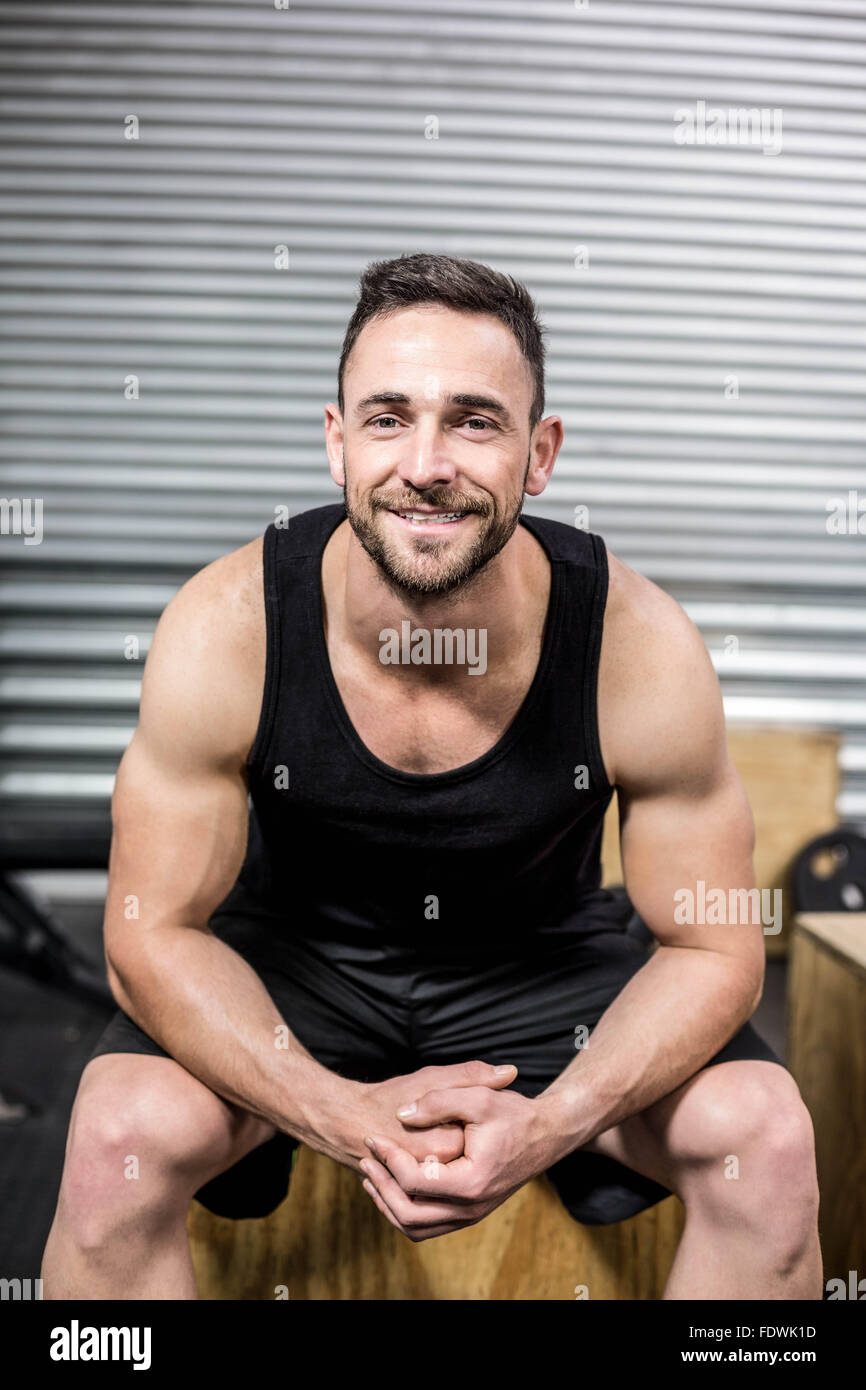 Fit man sitting on wooden box Stock Photo - Alamy