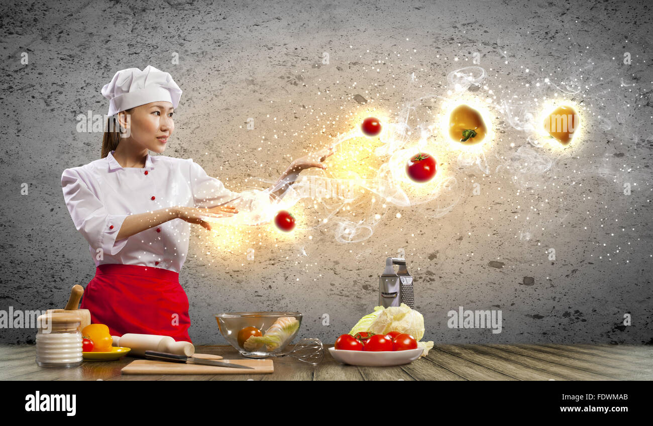 Asian female cooking with magic against color background Stock Photo ...