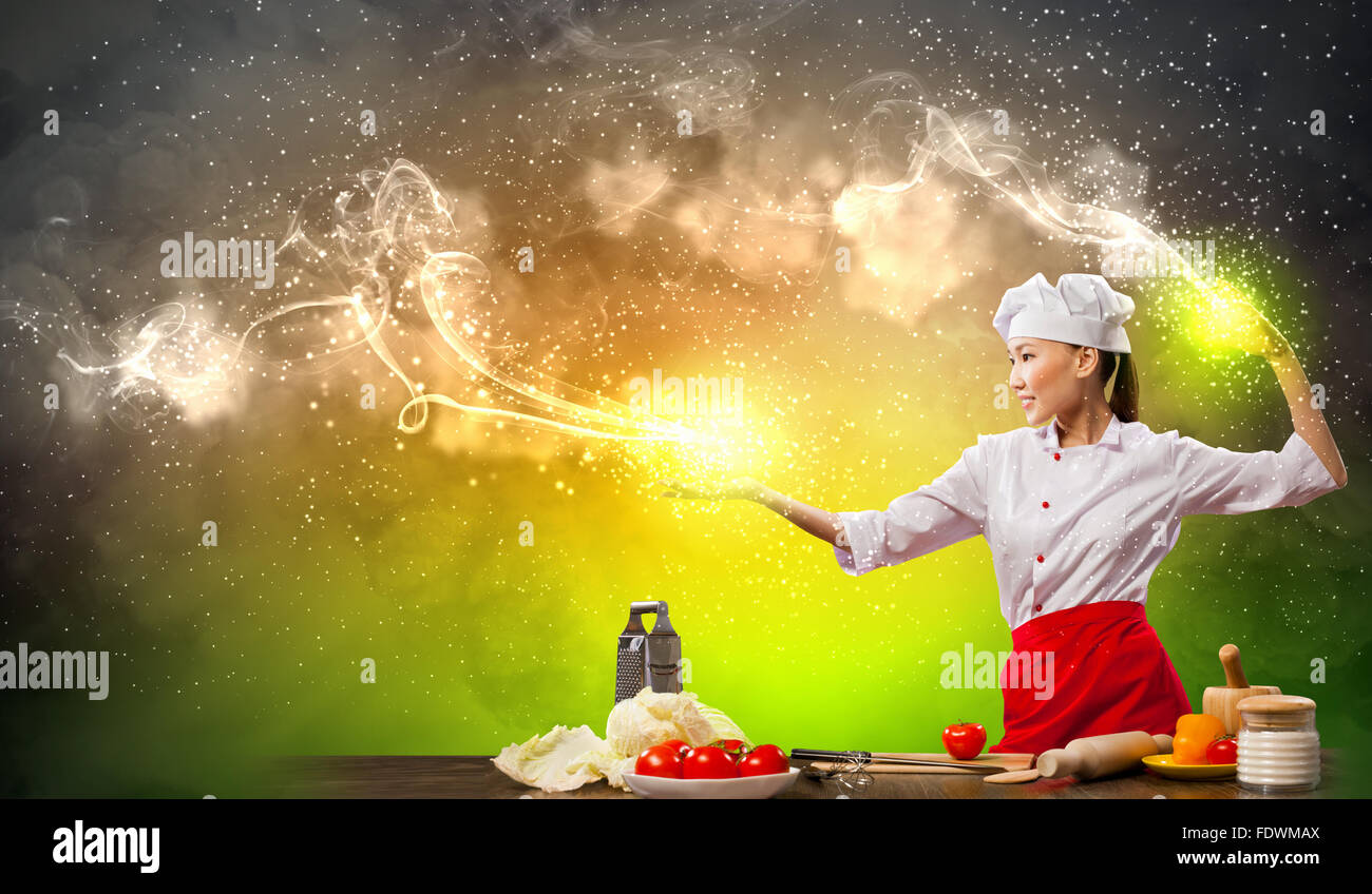 Asian female cooking with magic against color background Stock Photo ...