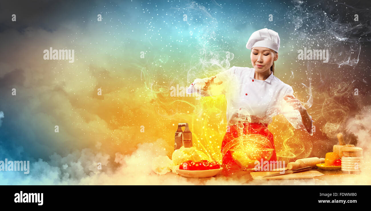 Asian female cooking with magic against color background Stock Photo ...