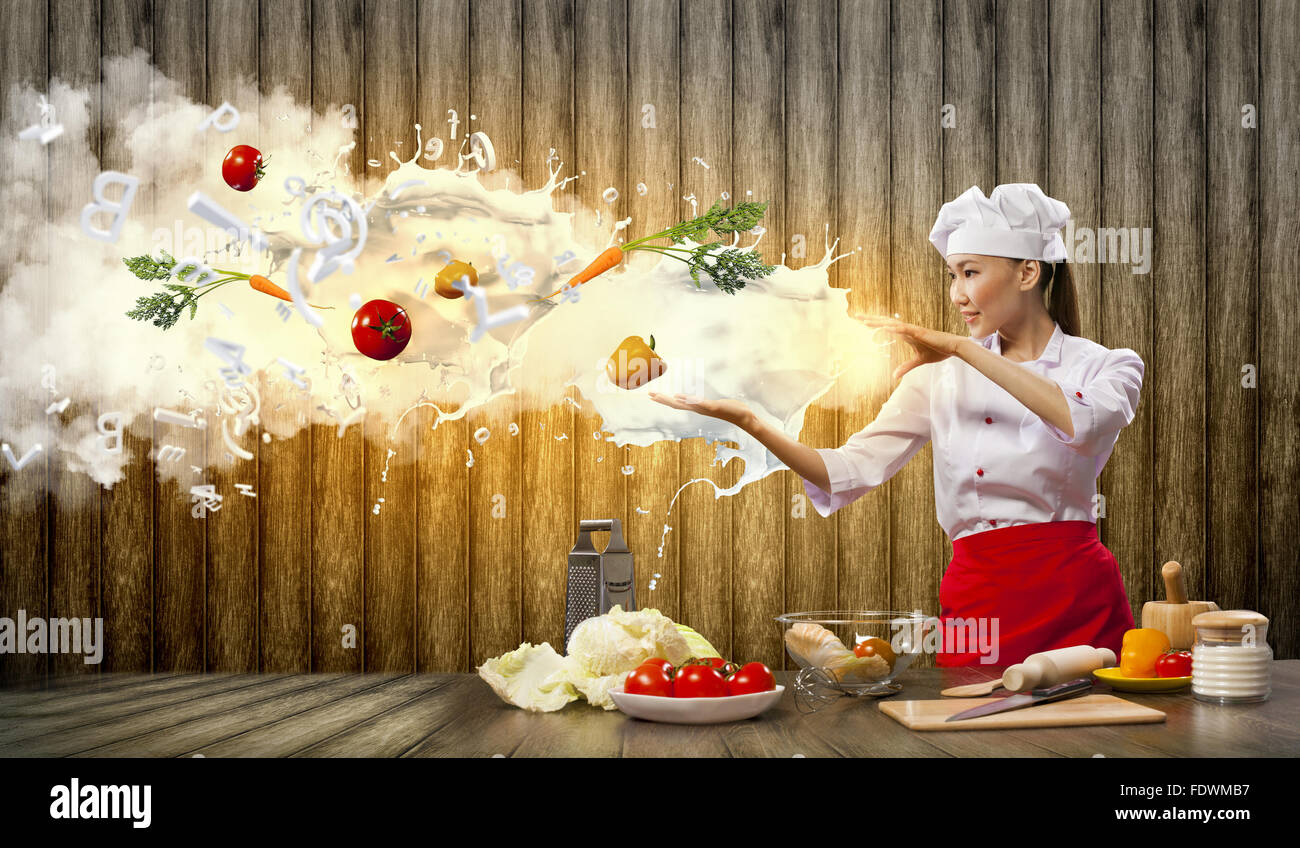 Asian female cooking with magic against color background Stock Photo ...