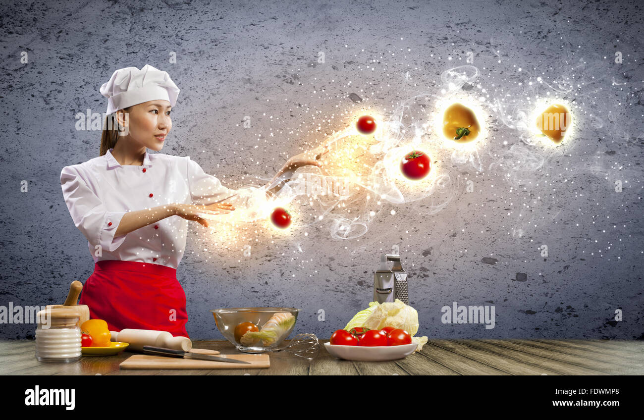 Asian female cooking with magic against color background Stock Photo ...