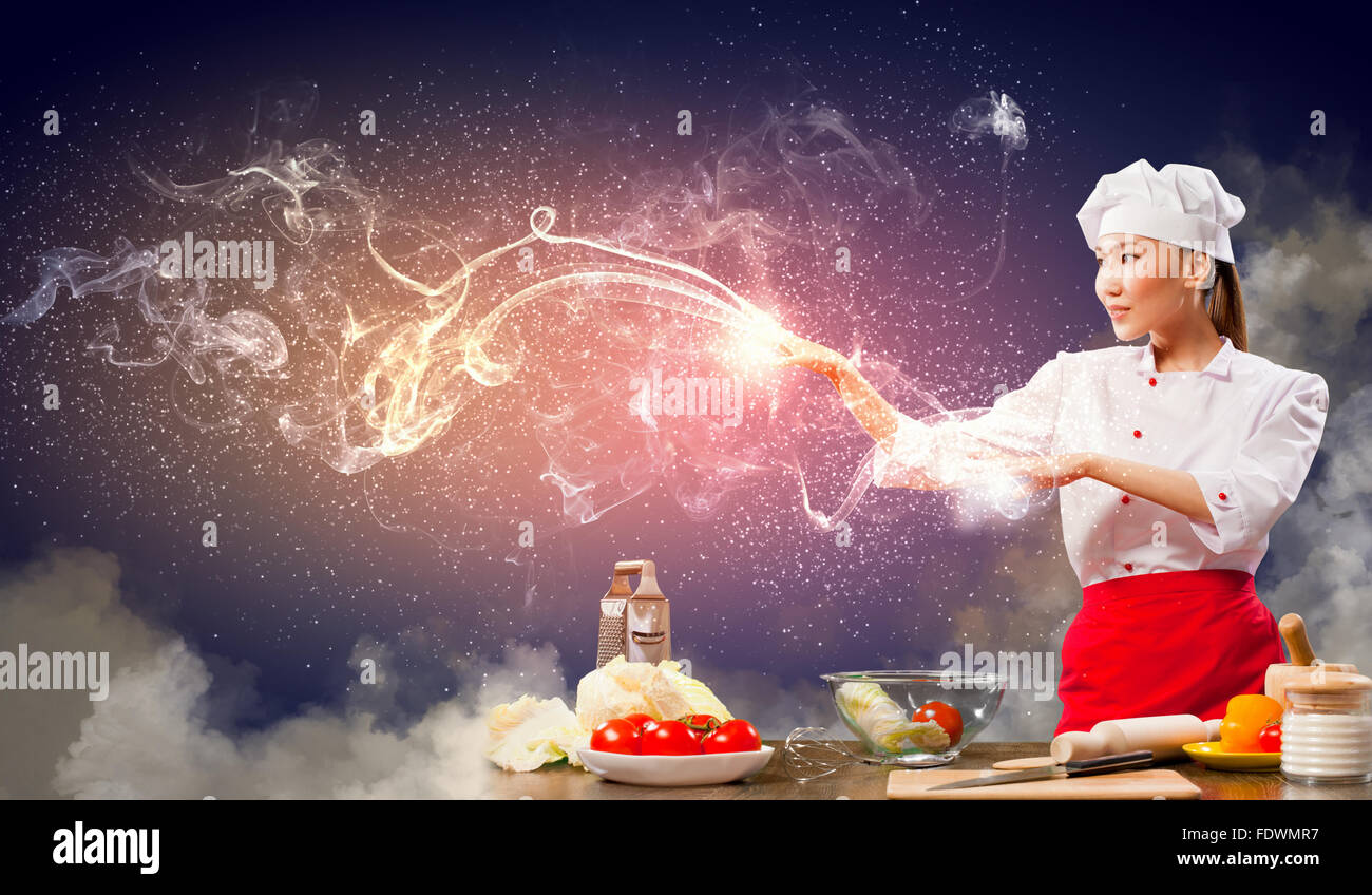 Asian female cooking with magic against color background Stock Photo ...