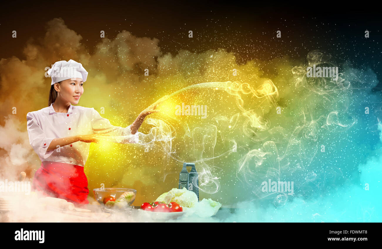 Asian female cooking with magic against color background Stock Photo ...