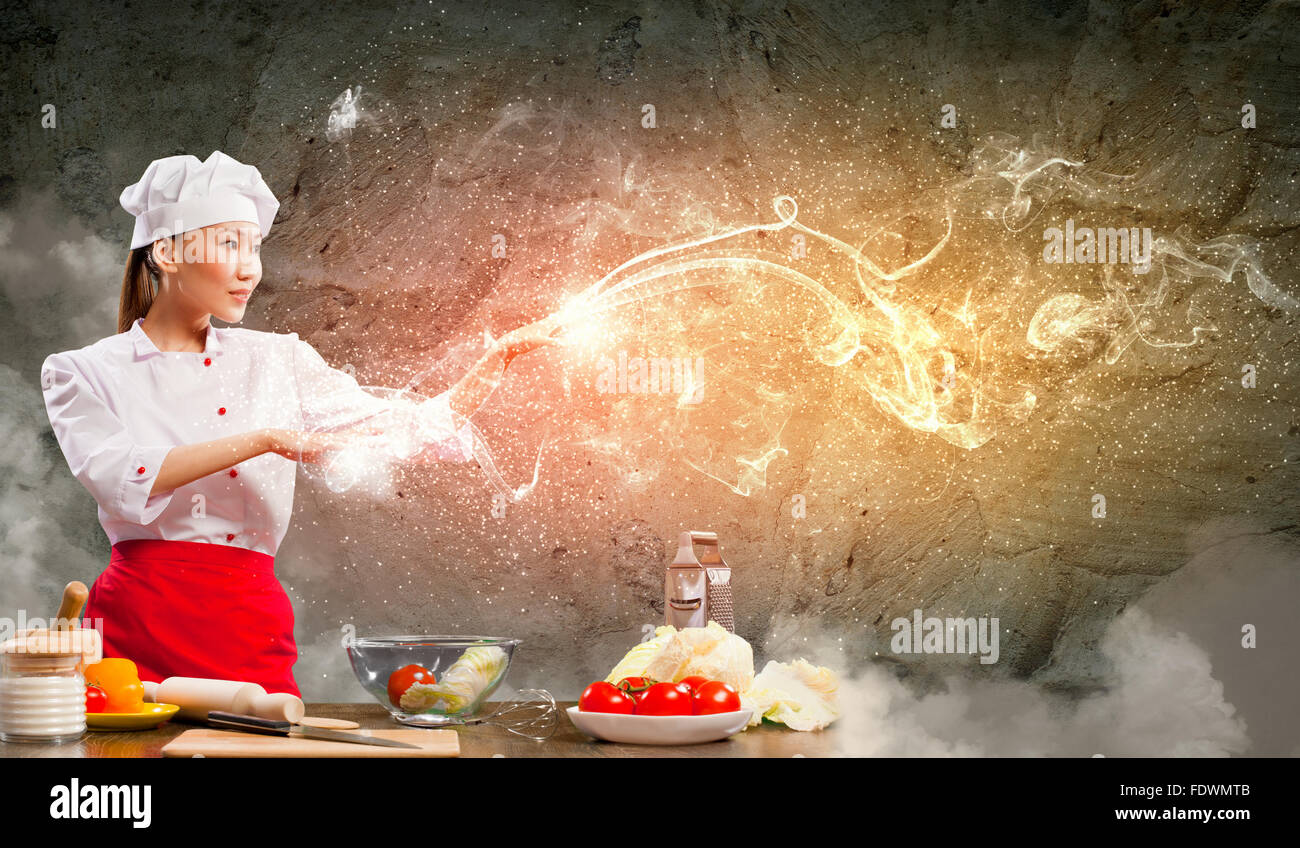 Asian female cooking with magic against color background Stock Photo ...