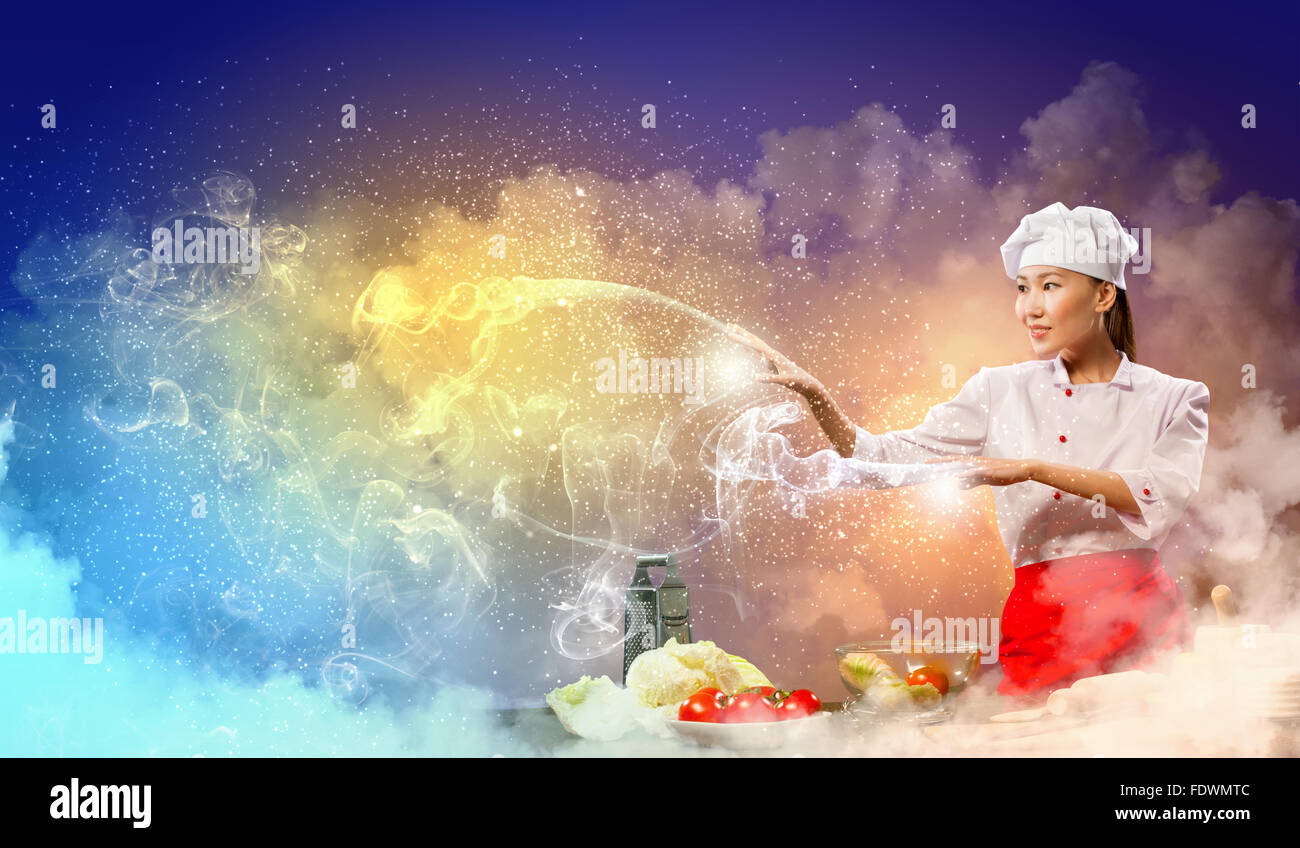 Asian female cooking with magic against color background Stock Photo ...