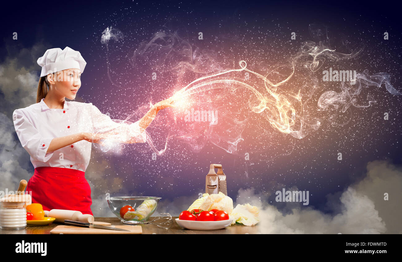 Asian female cooking with magic against color background Stock Photo ...