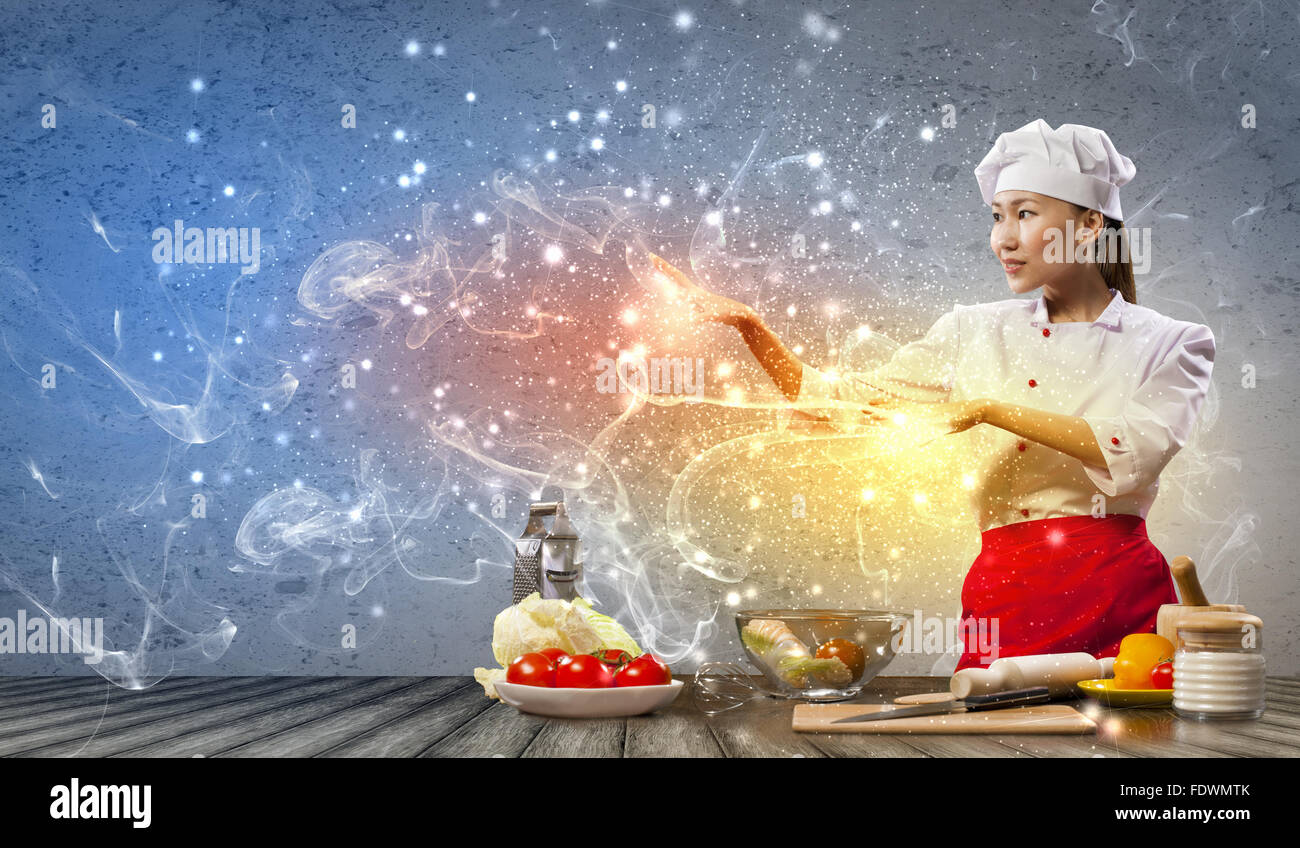 Asian female cooking with magic against color background Stock Photo ...